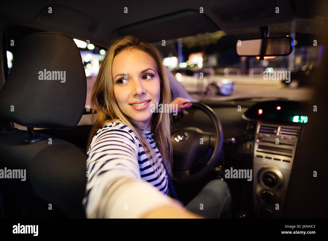 Beautiful young woman driving her car at night Stock Photo - Alamy