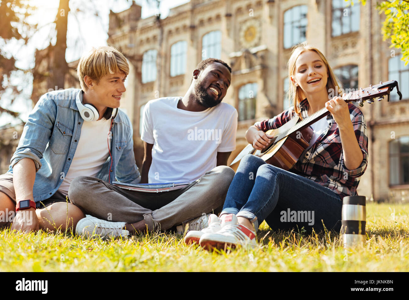 Lively sincere guys enjoying their friends song Stock Photo - Alamy