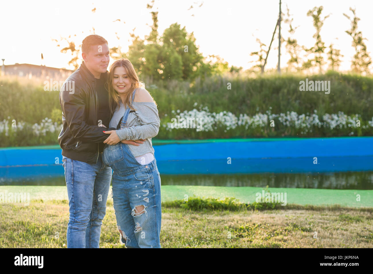 Happy and young pregnant couple hugging in nature Stock Photo - Alamy