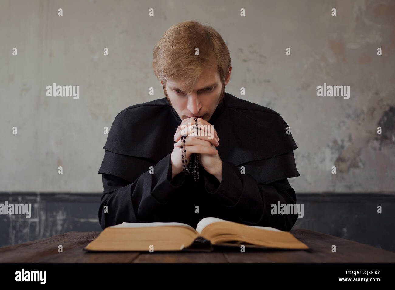 Priest read the Bible. Handsome young catholic priest praying to God ...