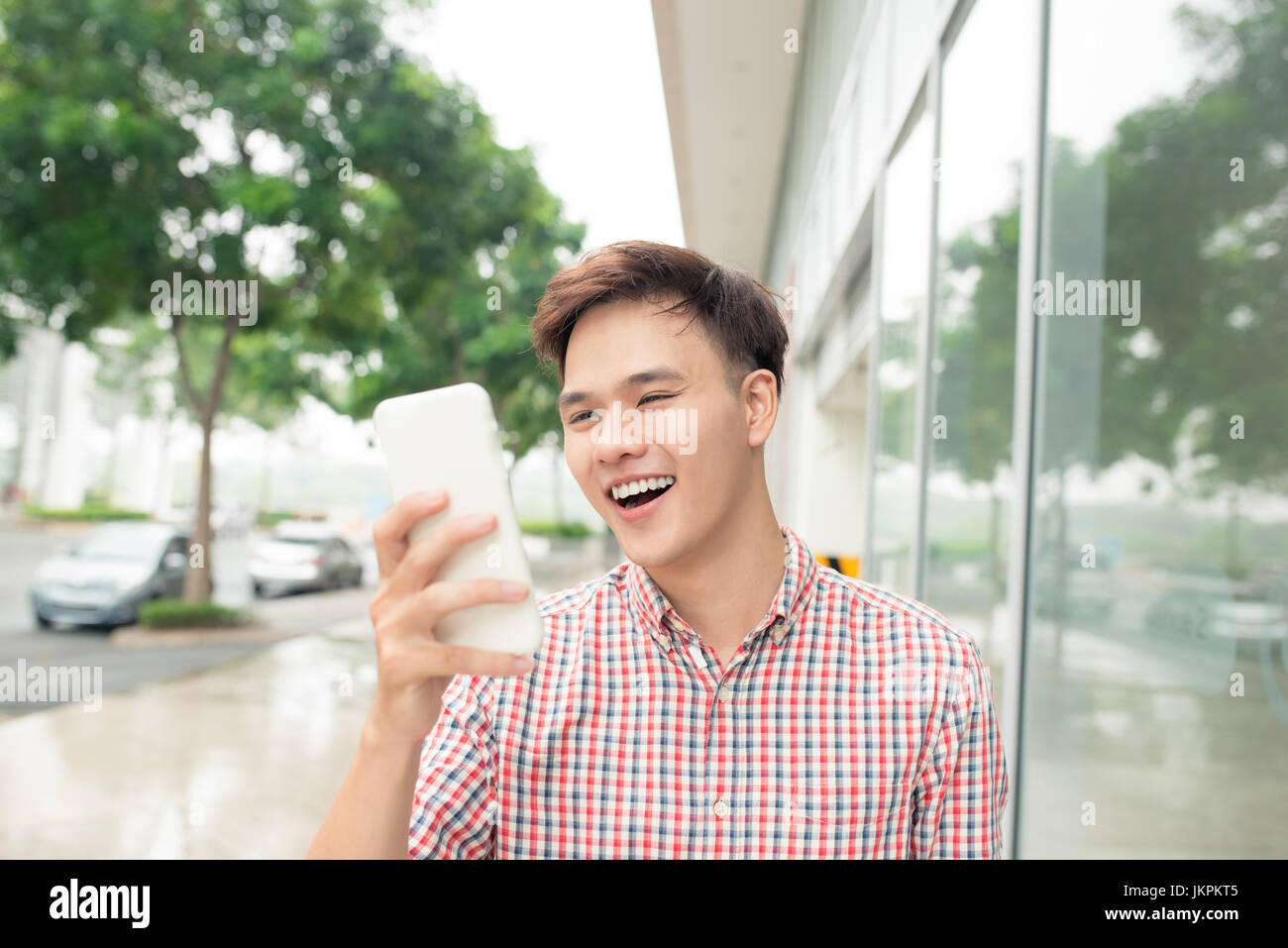 Cheerful handsome man checking something on mobile phone Stock Photo ...