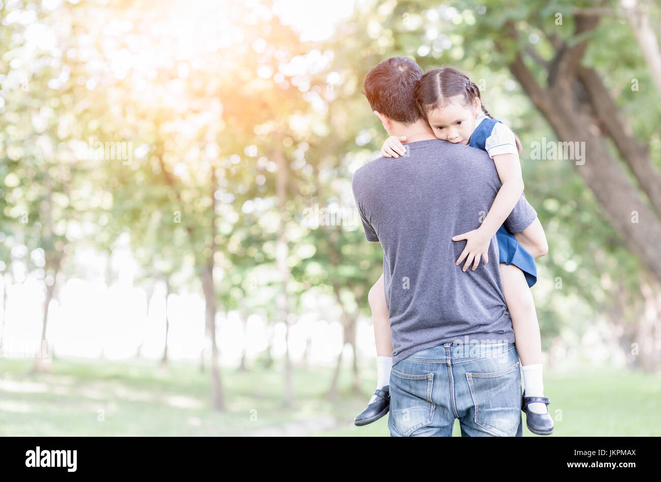 father carrying and encourage his daughter in uniform student on park ...