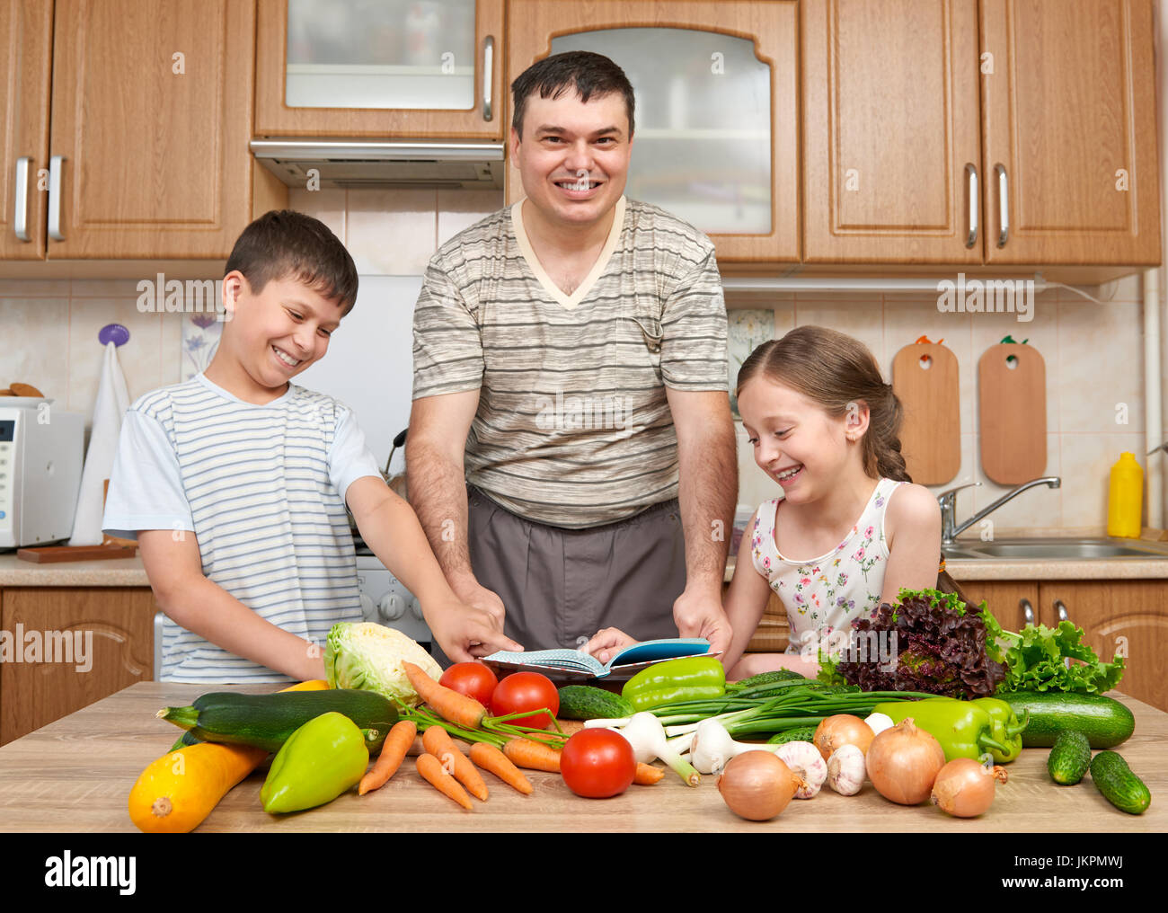 Father and two children reading cooking book and choice dishes. Happy ...