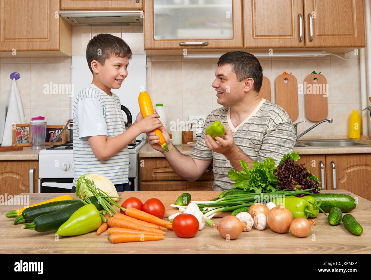 Father and son having fun with vegetables in home kitchen interior. Man ...
