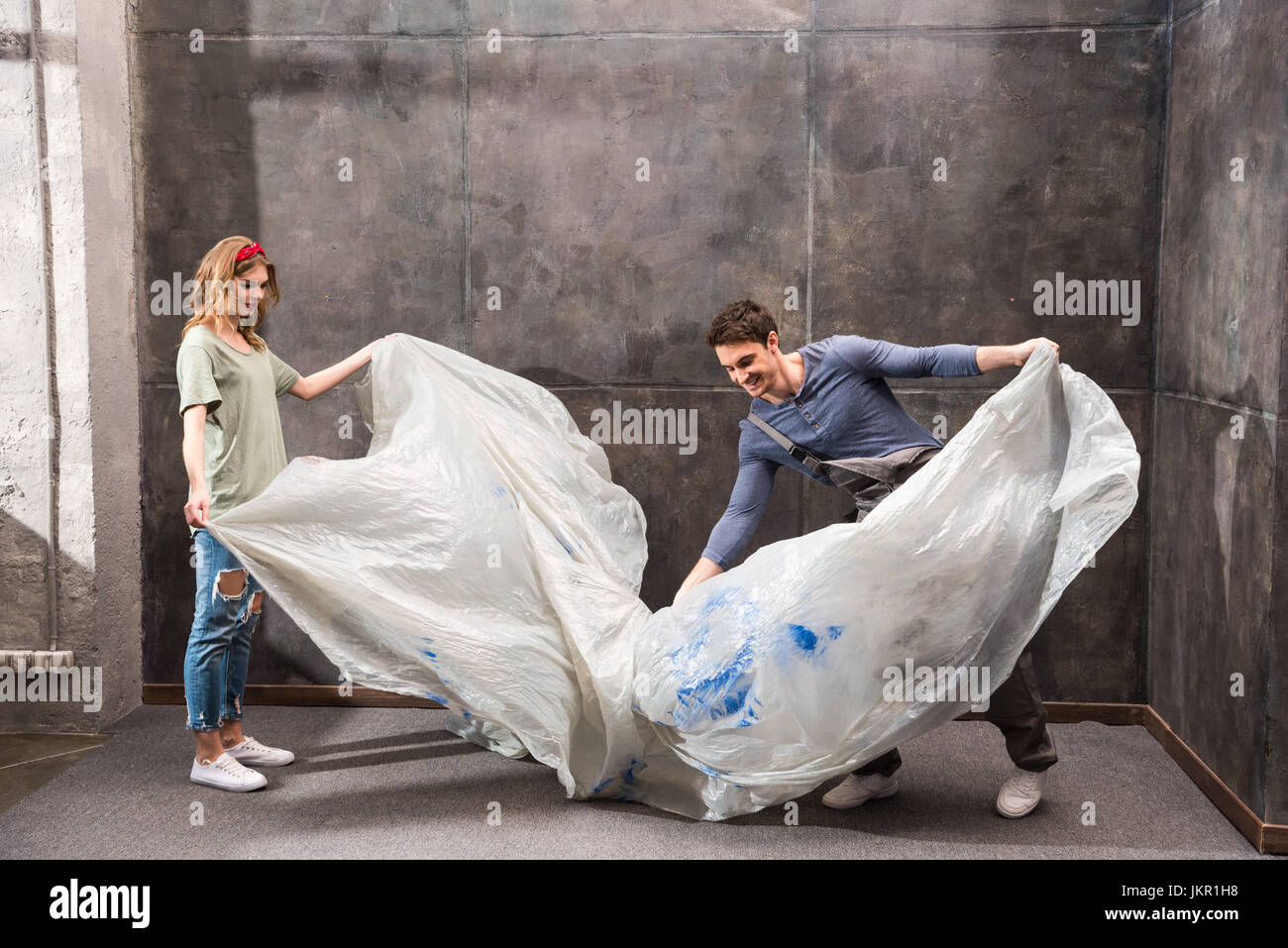 Smiling young professional couple preparing room for renovation home ...