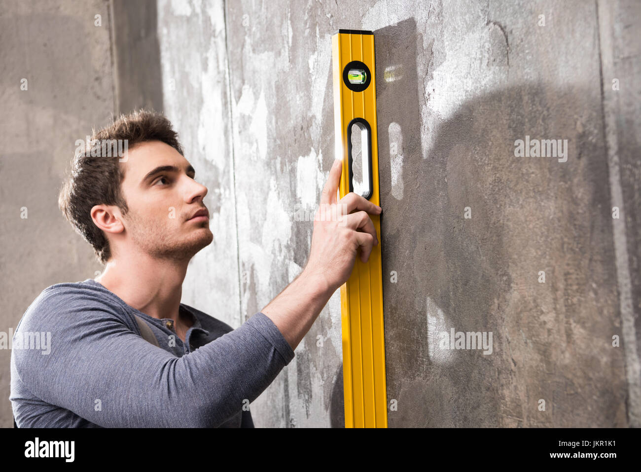 Professional young worker measuring wall with level tool, renovation ...