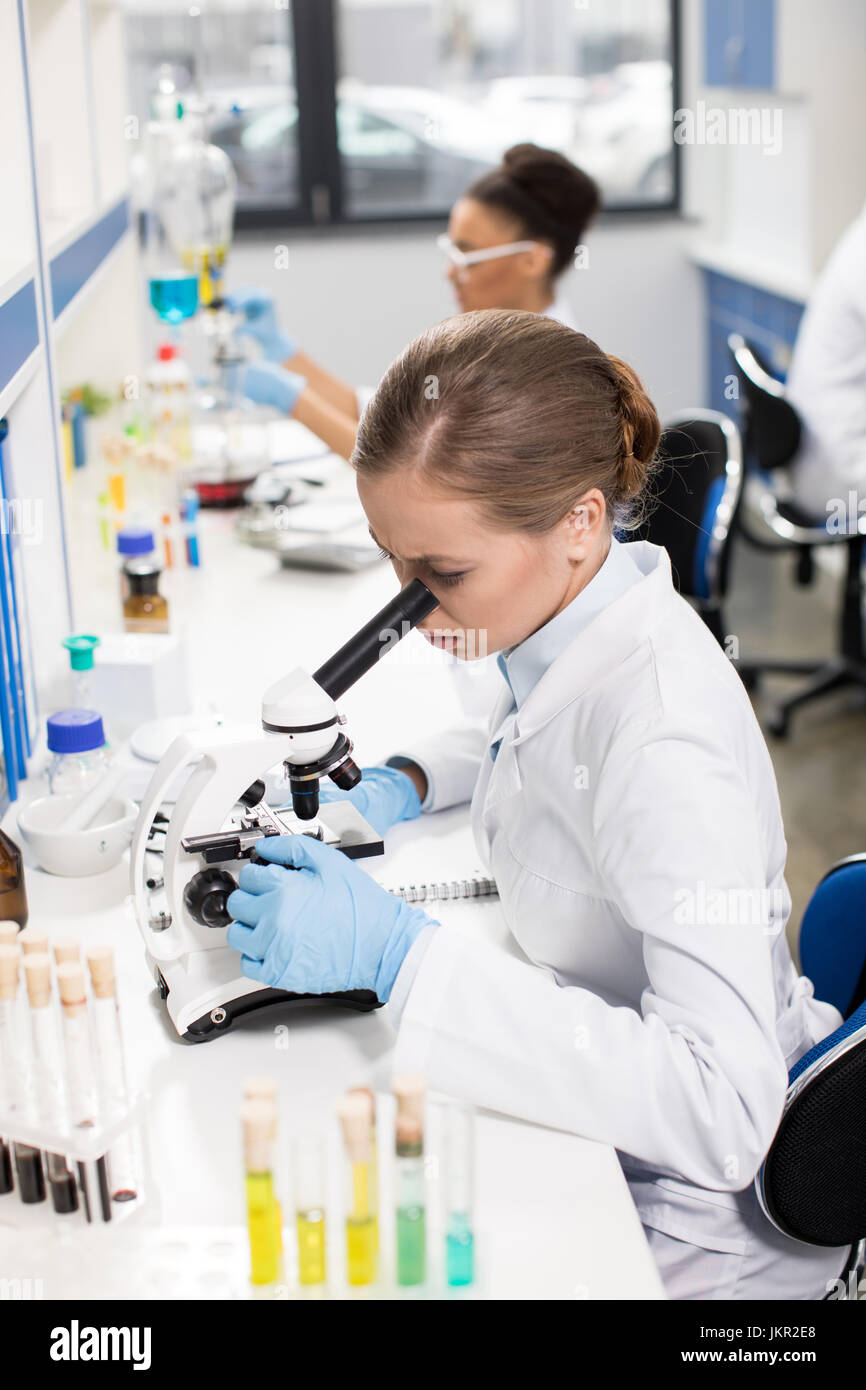 Focused young scientist working with microscope in research laboratory ...