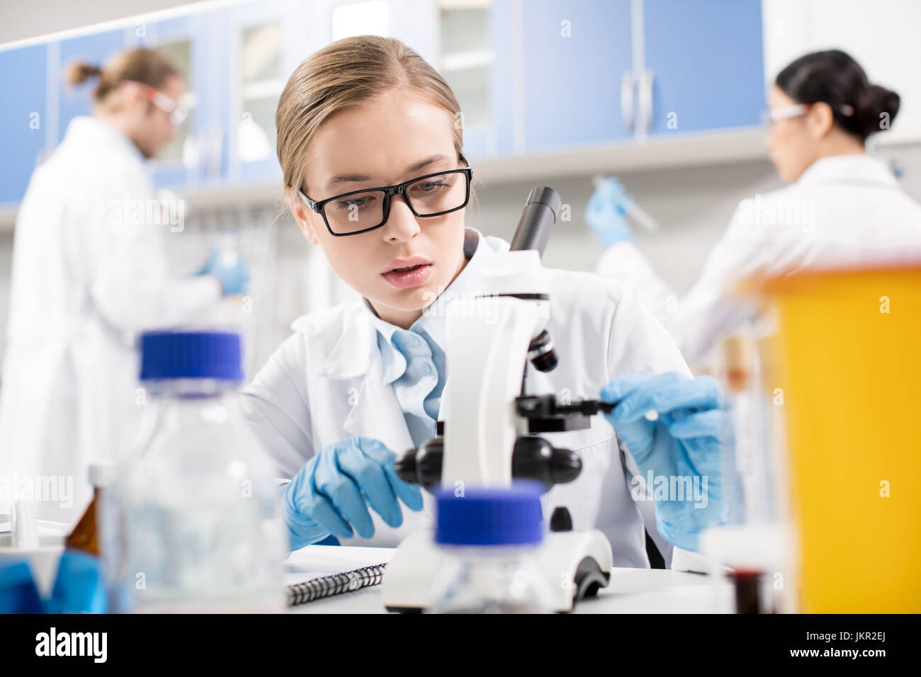 Focused young scientist working with microscope in research laboratory ...