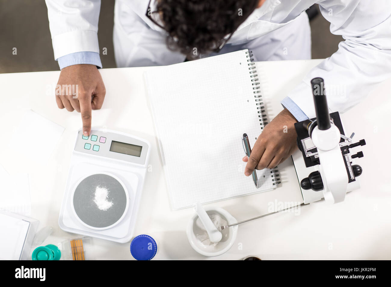 Overhead view of young scientist working with electronic scales and ...