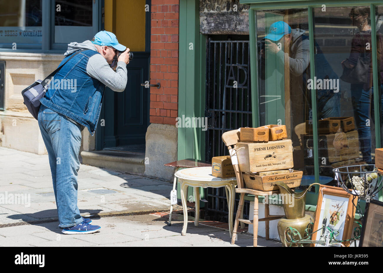 Photographer taking a photo through a shop window with his reflection ...