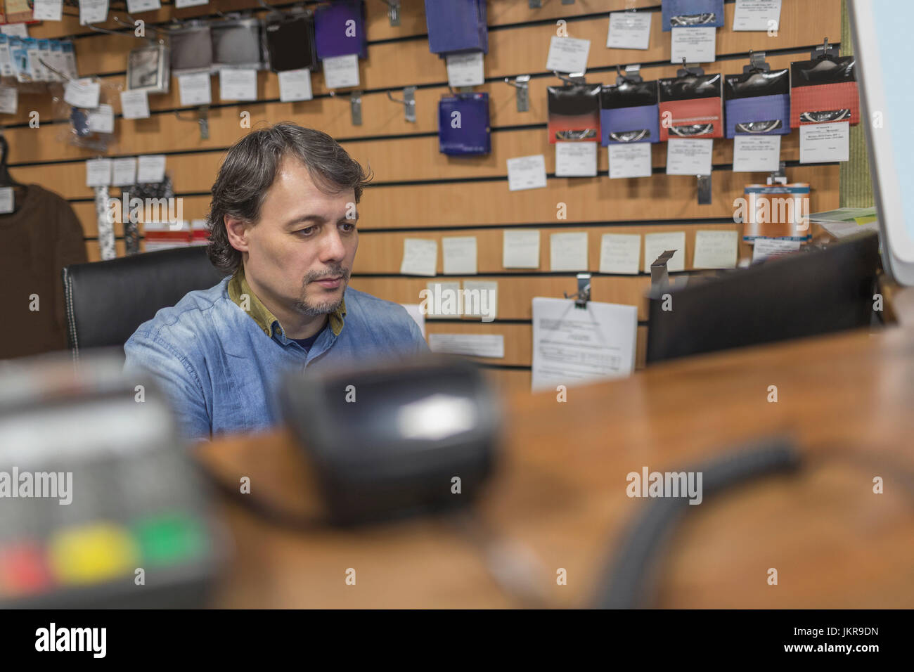 Owner sitting at checkout counter at store Stock Photo - Alamy