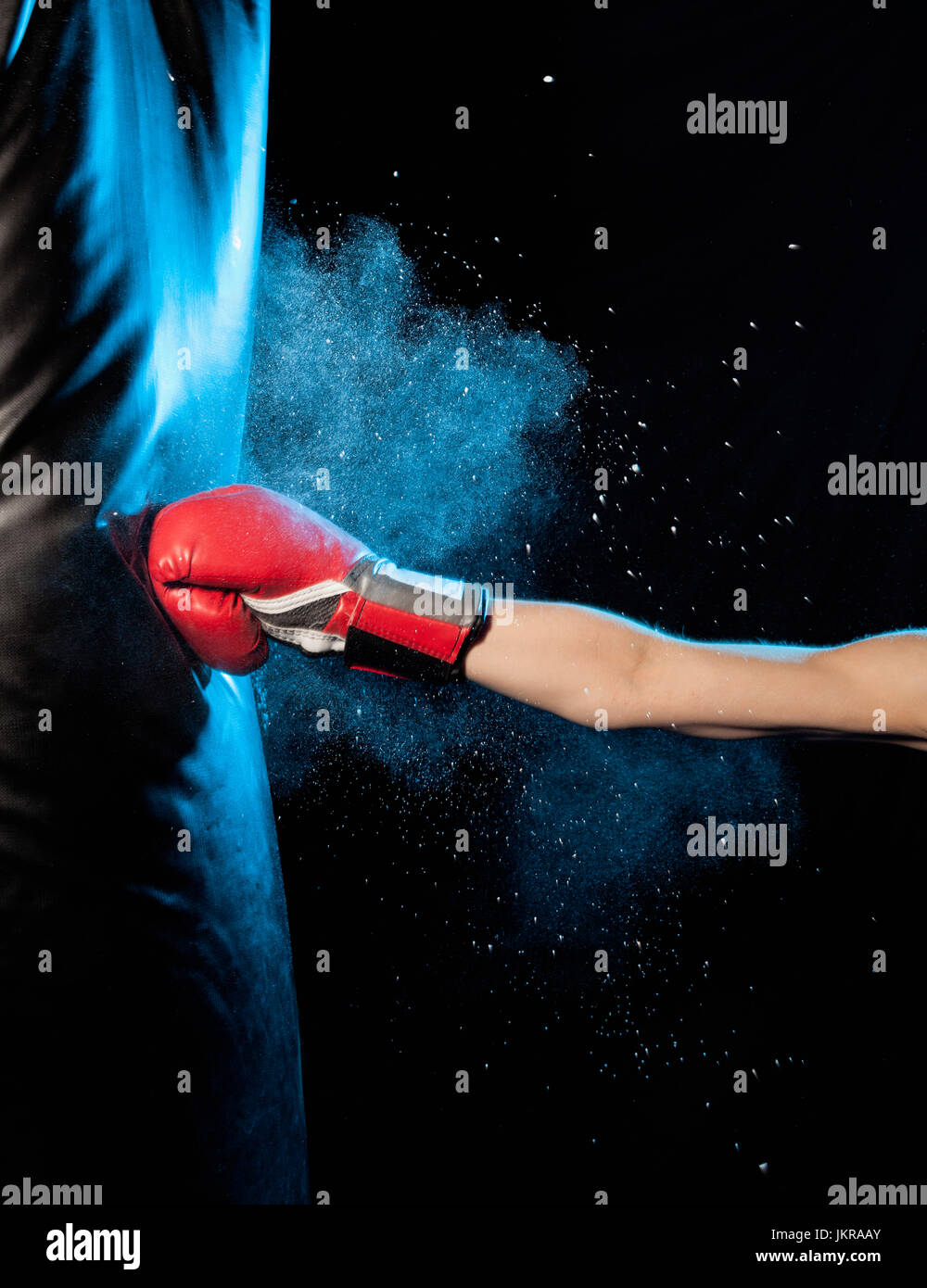 Cropped image of man hitting punching bag against black background ...
