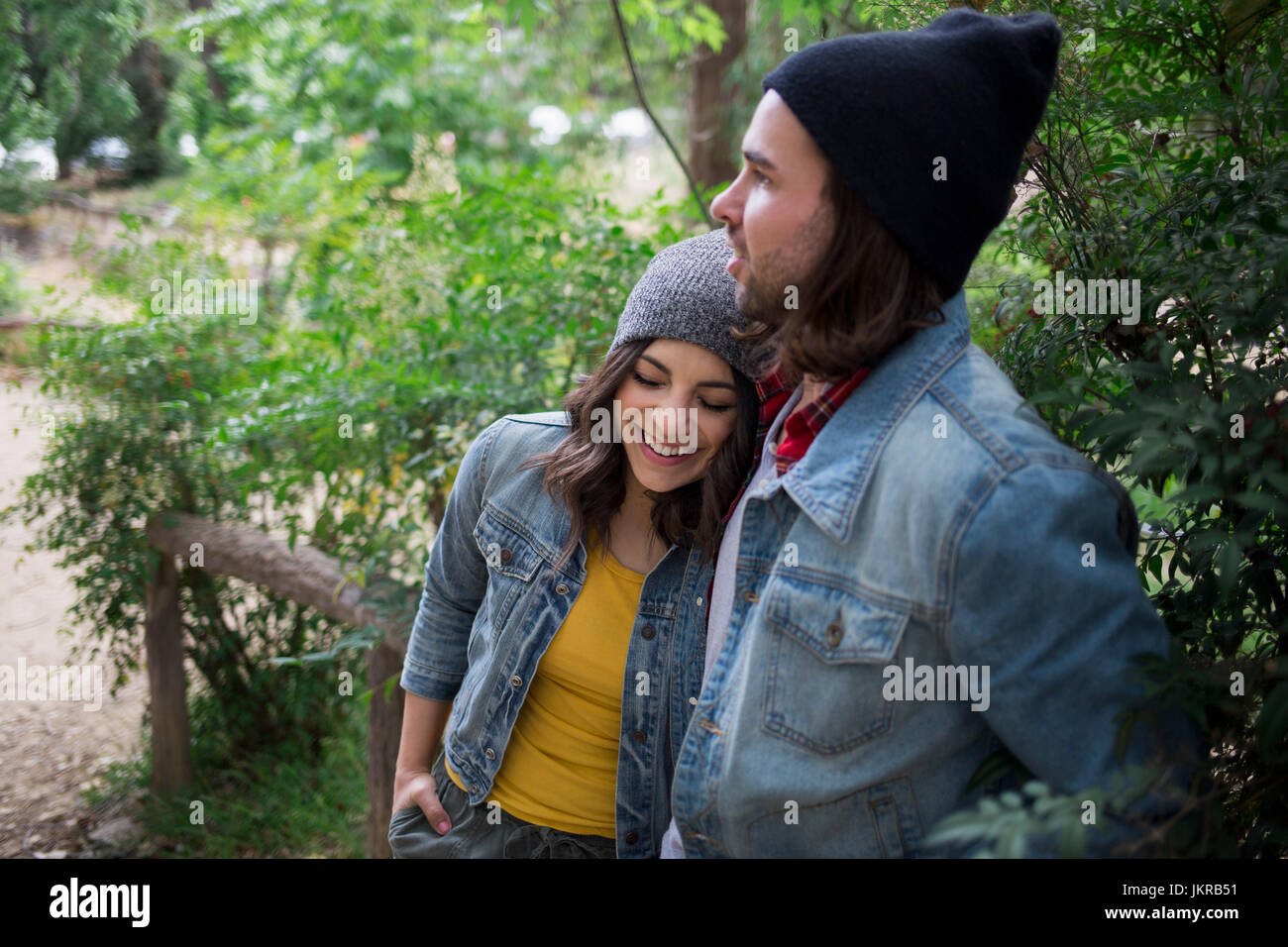 Affectionate couple wearing denim jackets and knit hats at park Stock ...