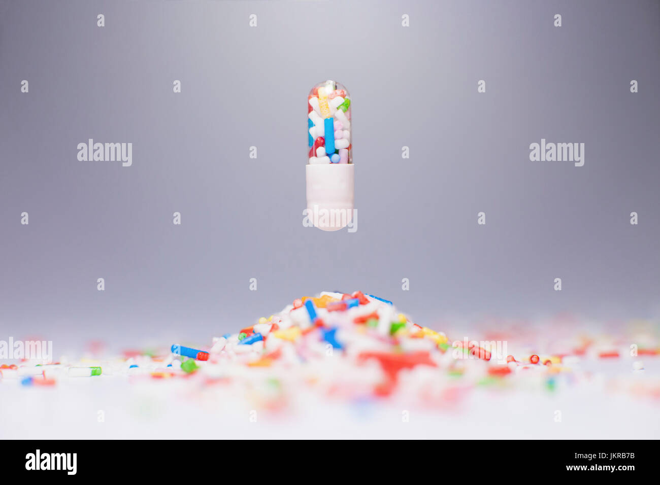 Capsule containing sprinkles in mid-air against gray background Stock ...