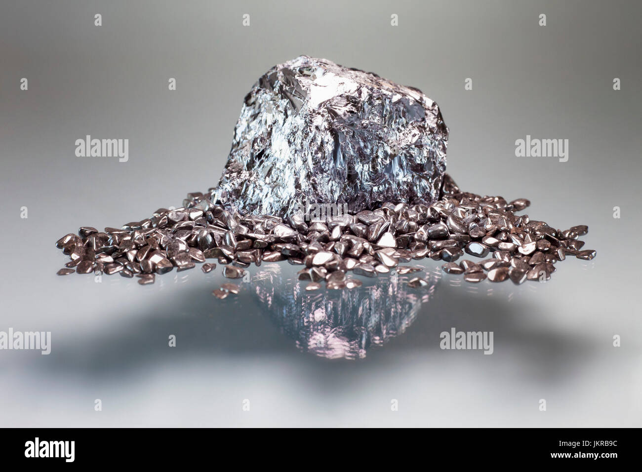 Shiny stone surrounded by pebbles with reflection against gray ...