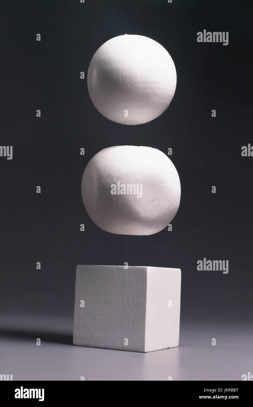 Spheres levitating over white block shape against gray background Stock ...