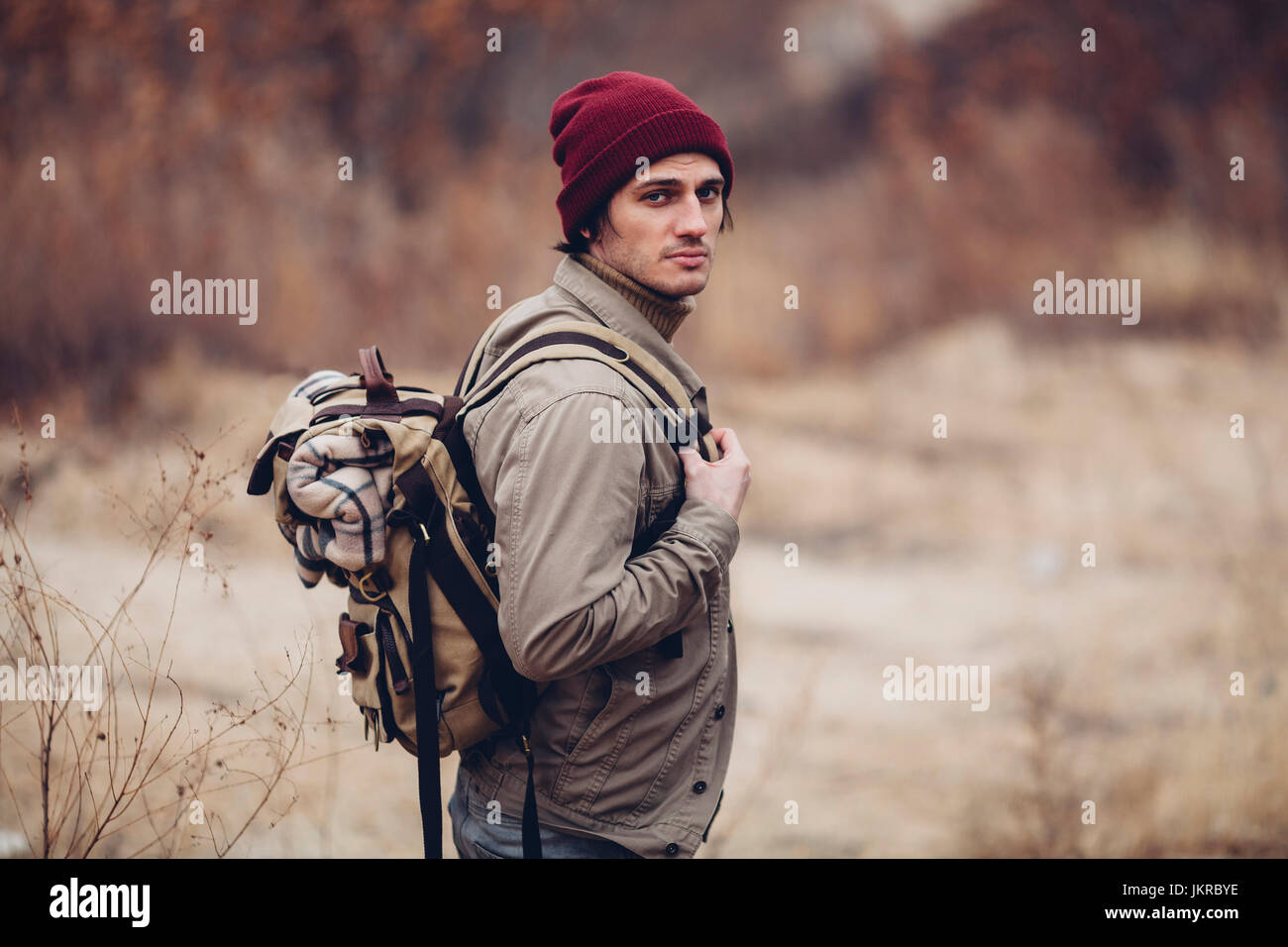 Portrait of man carrying backpack and standing in field Stock Photo - Alamy