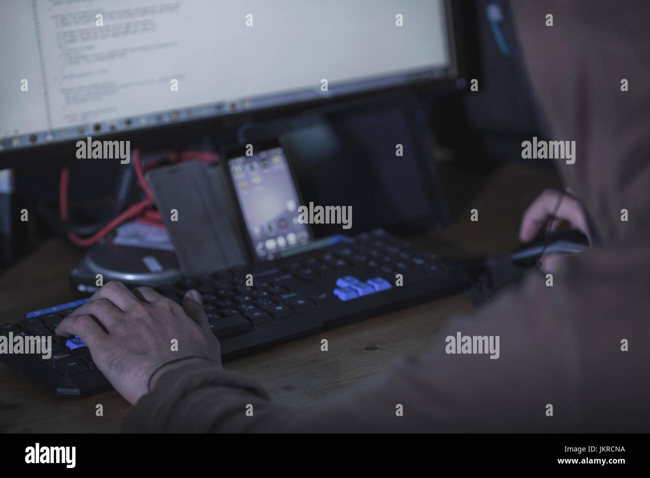 Cropped image of computer hacker with smart phone at table Stock Photo ...