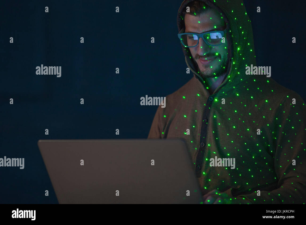 Green lights over smiling computer hacker wearing hooded shirt using ...