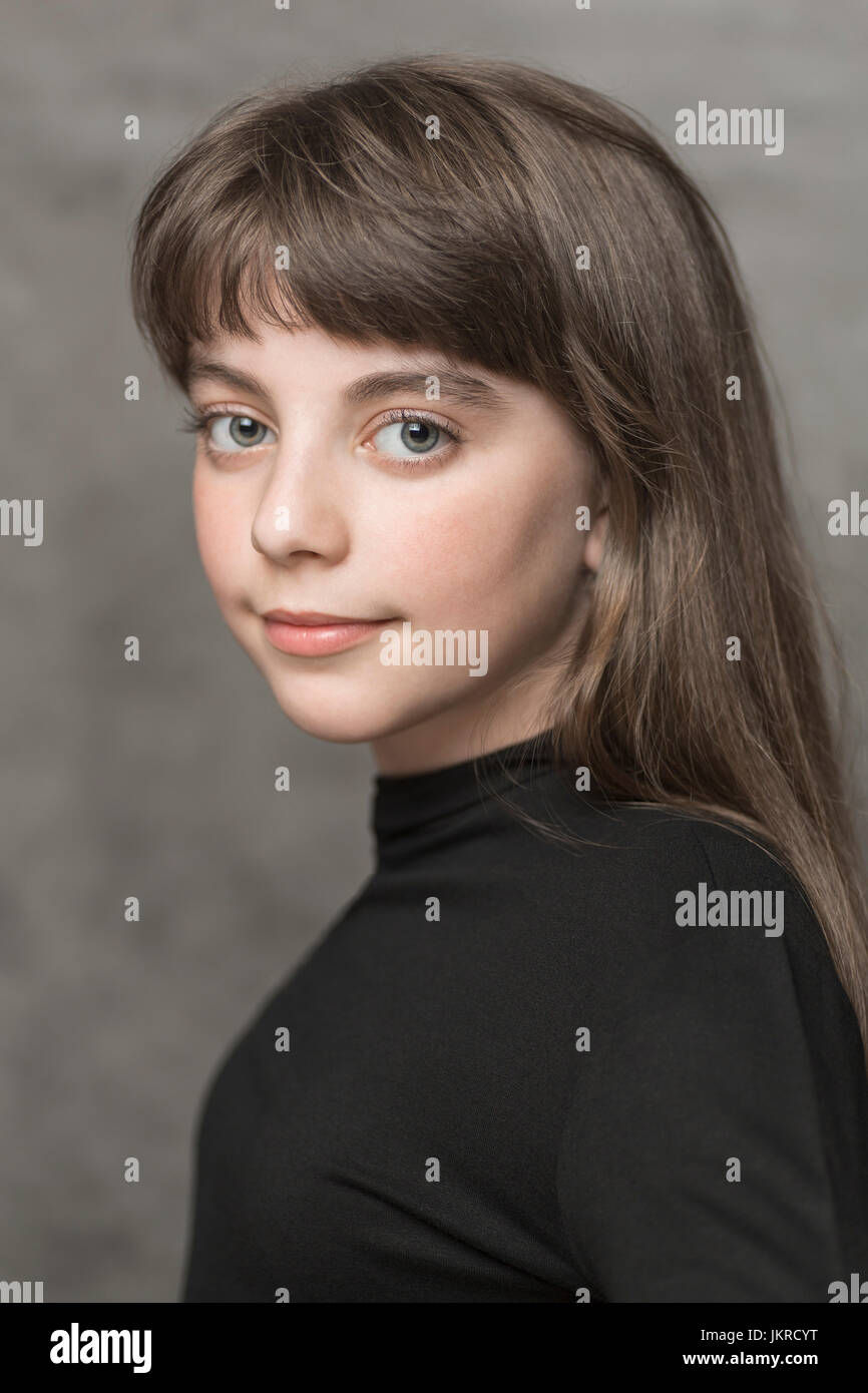 Side view portrait of smiling girl with long hair against gray ...