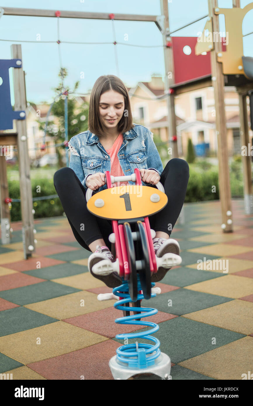 Full length of smiling woman sitting on spring ride at park Stock Photo ...
