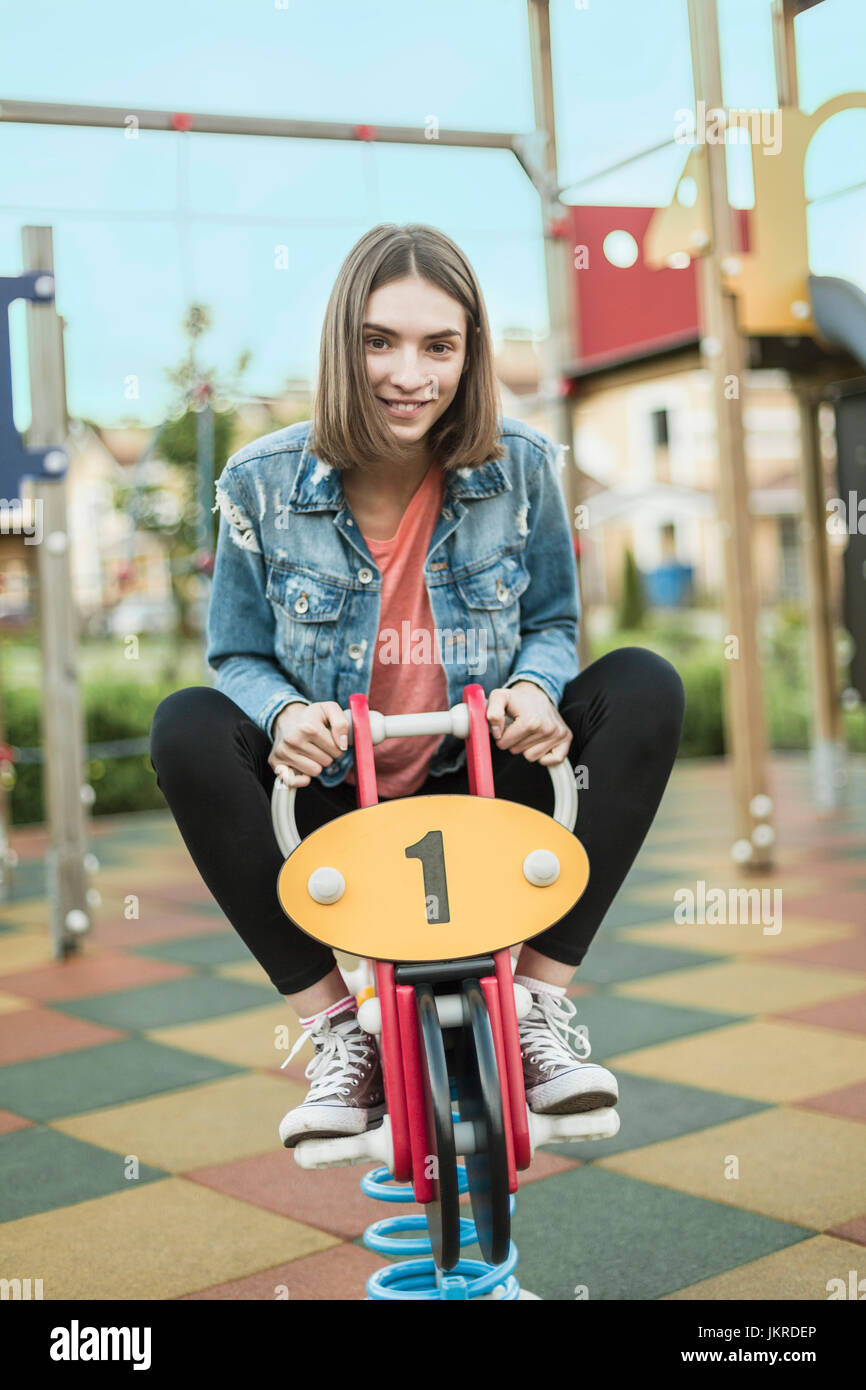 Full length portrait of happy woman sitting on spring ride at park ...