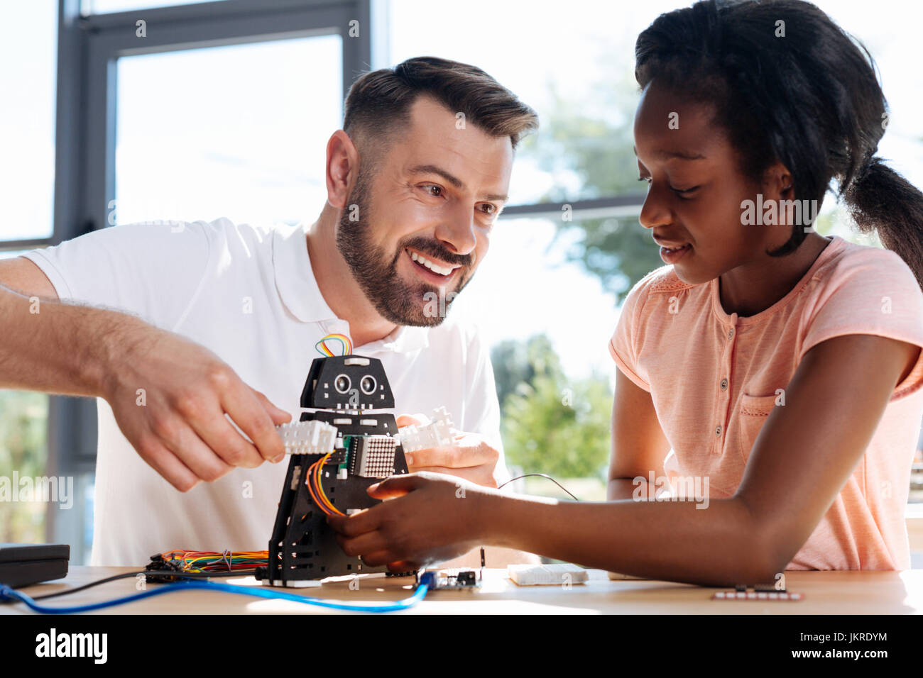Cheerful teacher and student playing with a robot Stock Photo - Alamy