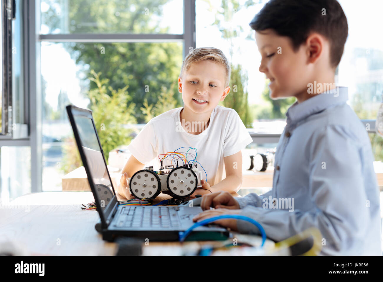 Pleasant boy looking at the screen of his friends laptop Stock Photo ...