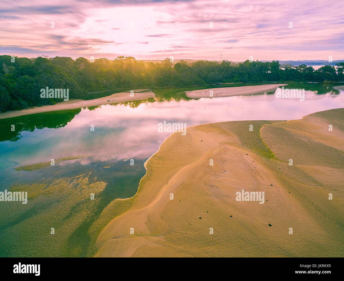 Aerial view of shallow ocean water, sand, and lush coastline vegetation ...