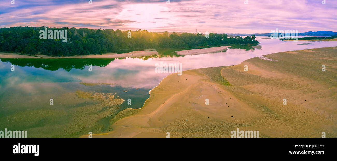 Aerial panoramic view of shallow ocean water, sand, and lush coastline ...