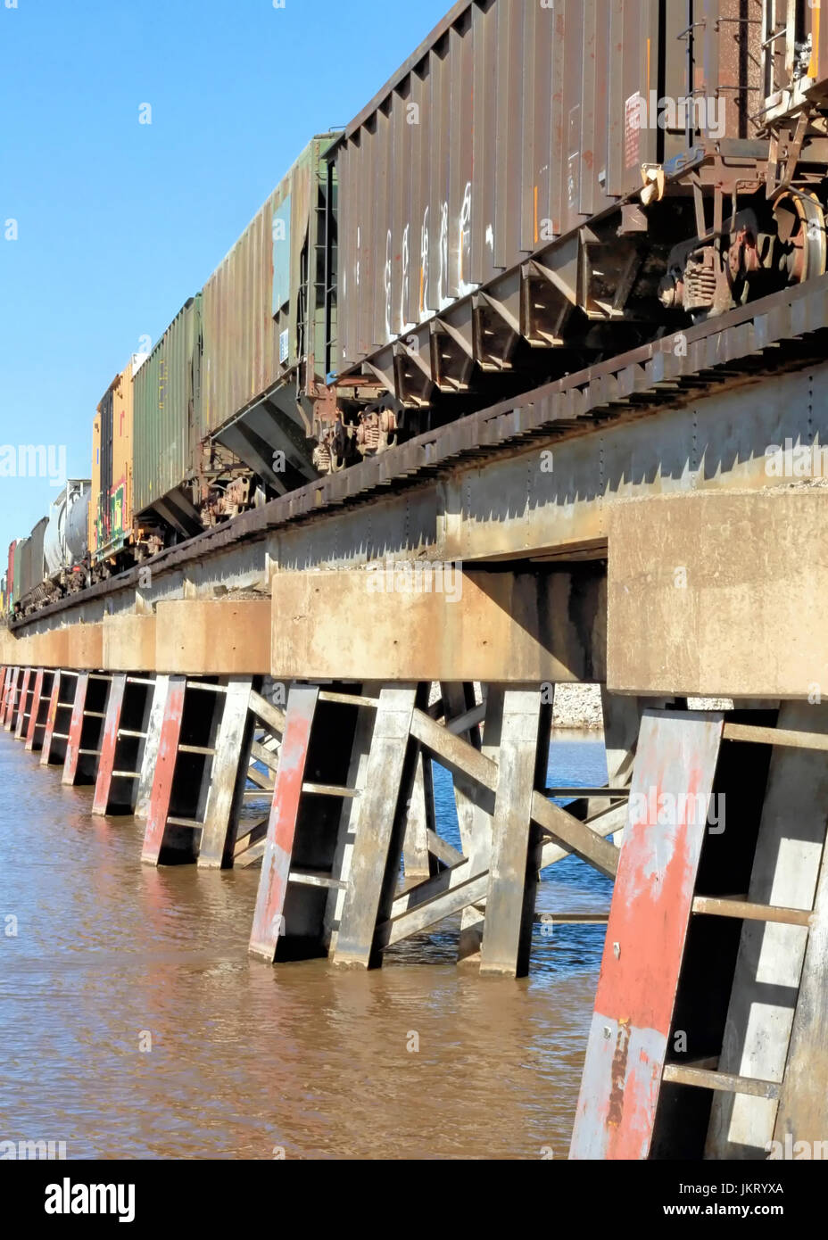 A line of railroad cars passes over a river on a sunny day Stock Photo ...