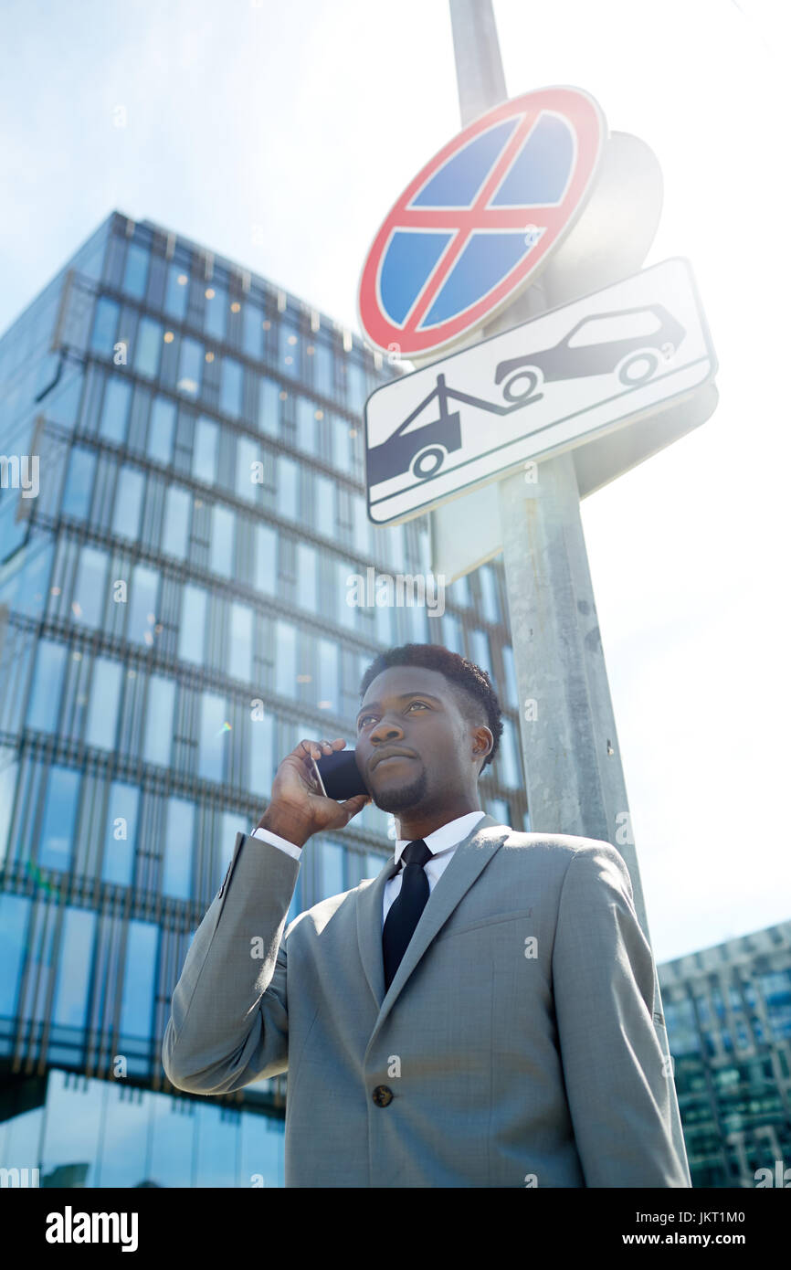 Businessman calling under warning sign outdoors Stock Photo - Alamy