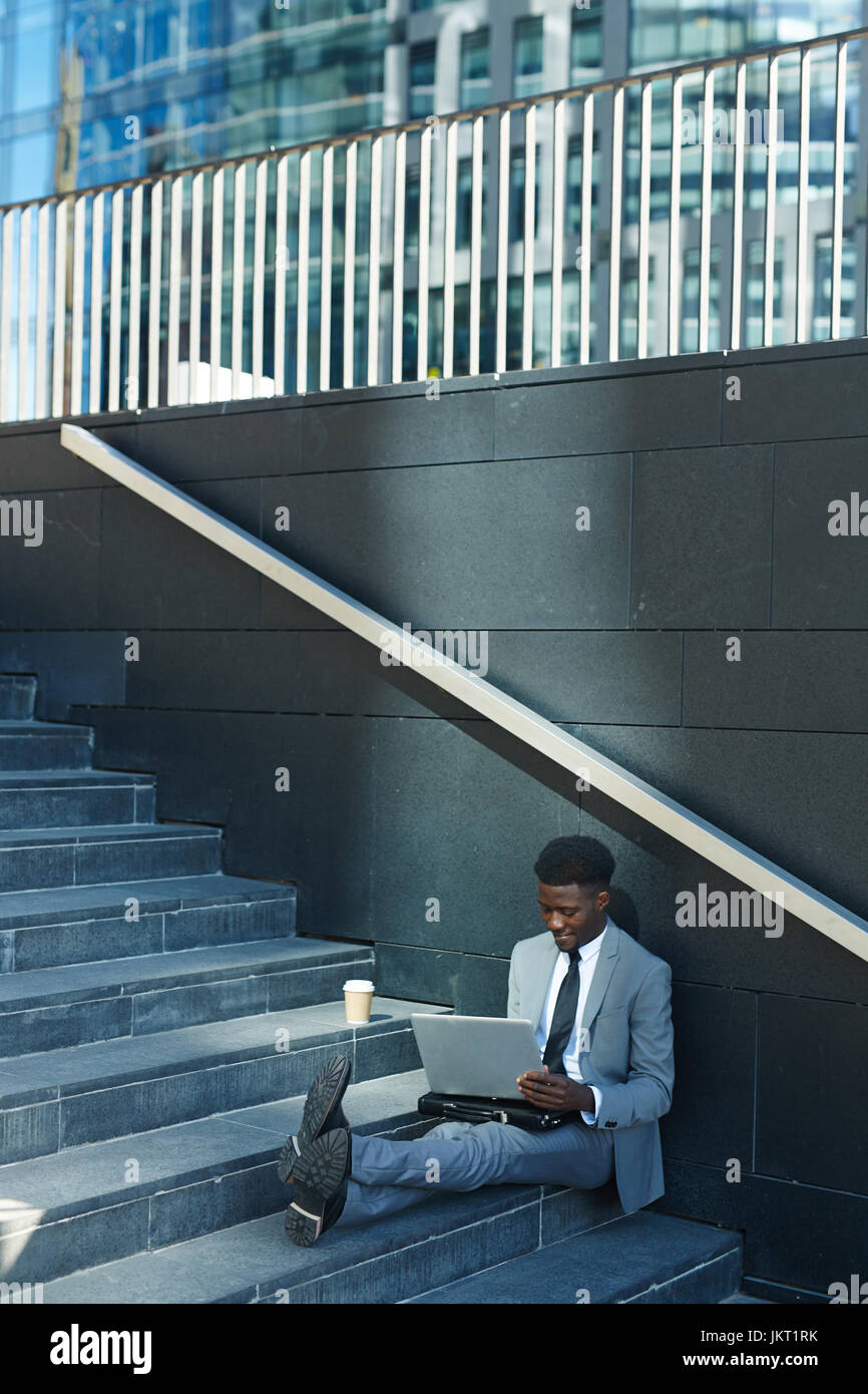 Young manager networking while sitting on staircase in urban ...