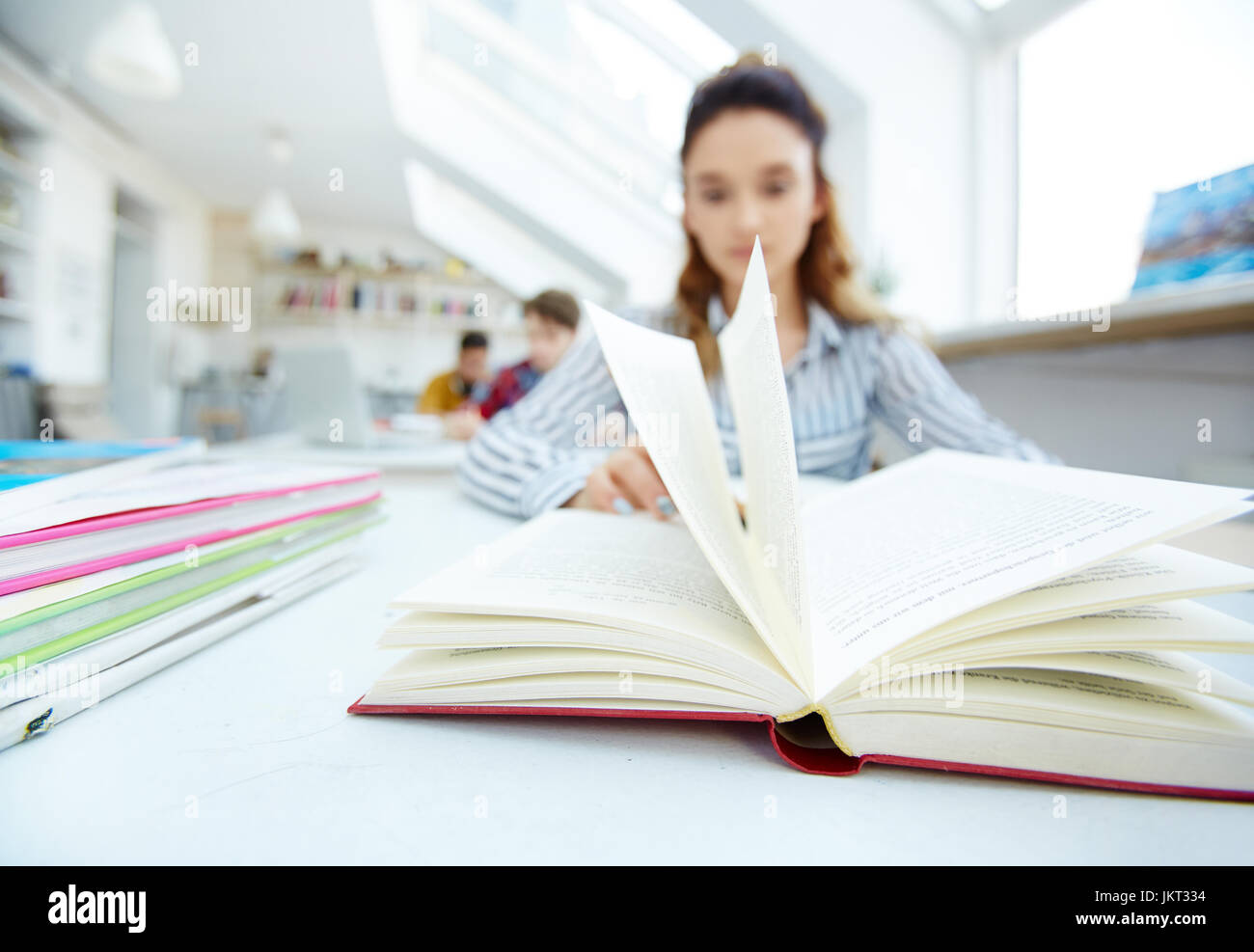 Student reading textbook in library while getting ready for school ...