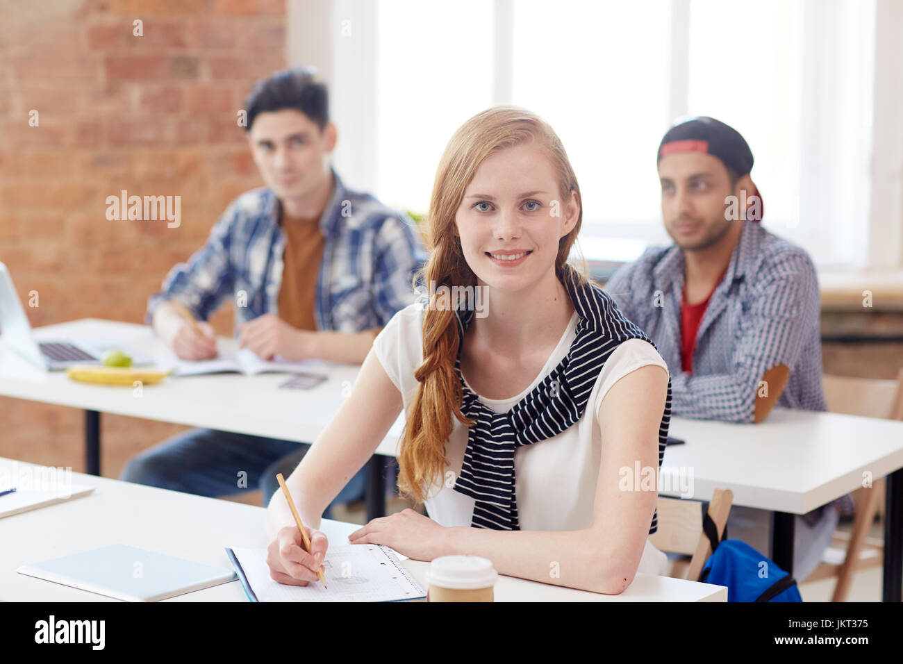 Diligent student sitting by desk at lecture Stock Photo - Alamy