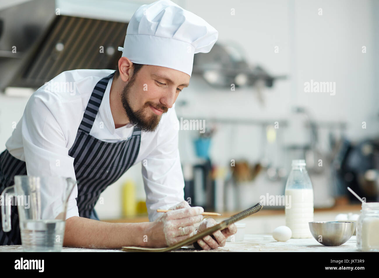 Young chef making notes in notepad Stock Photo - Alamy