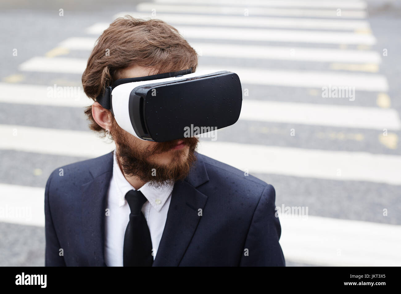Modern man wearing headset while crossing road Stock Photo - Alamy