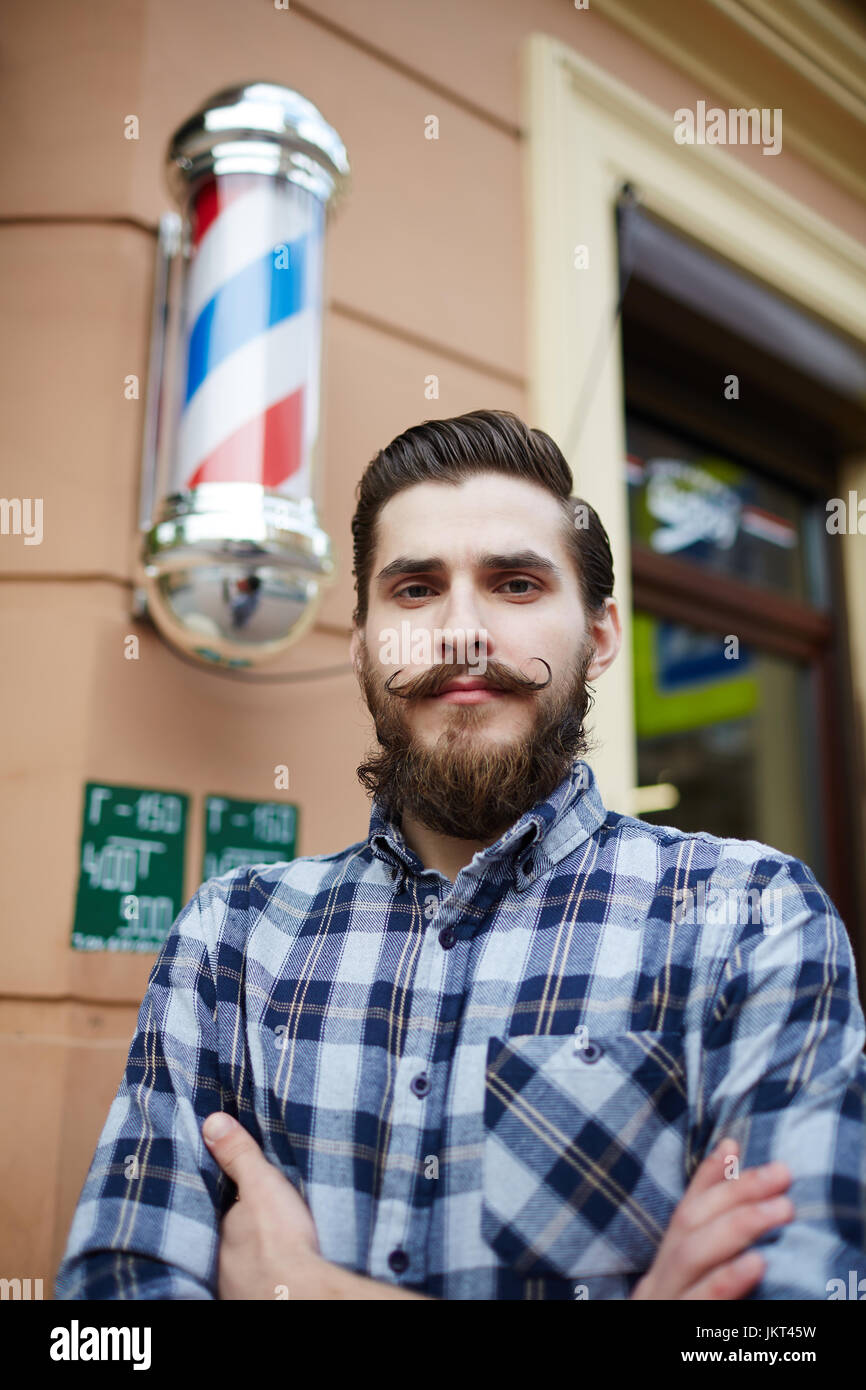 Young barber standing by barbershop Stock Photo - Alamy