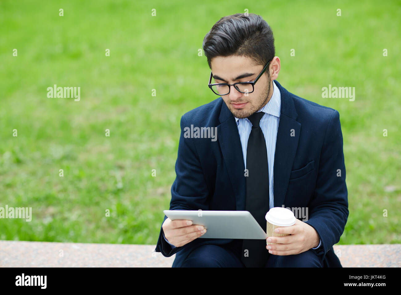 Man with drink watching something curious in tablet Stock Photo - Alamy