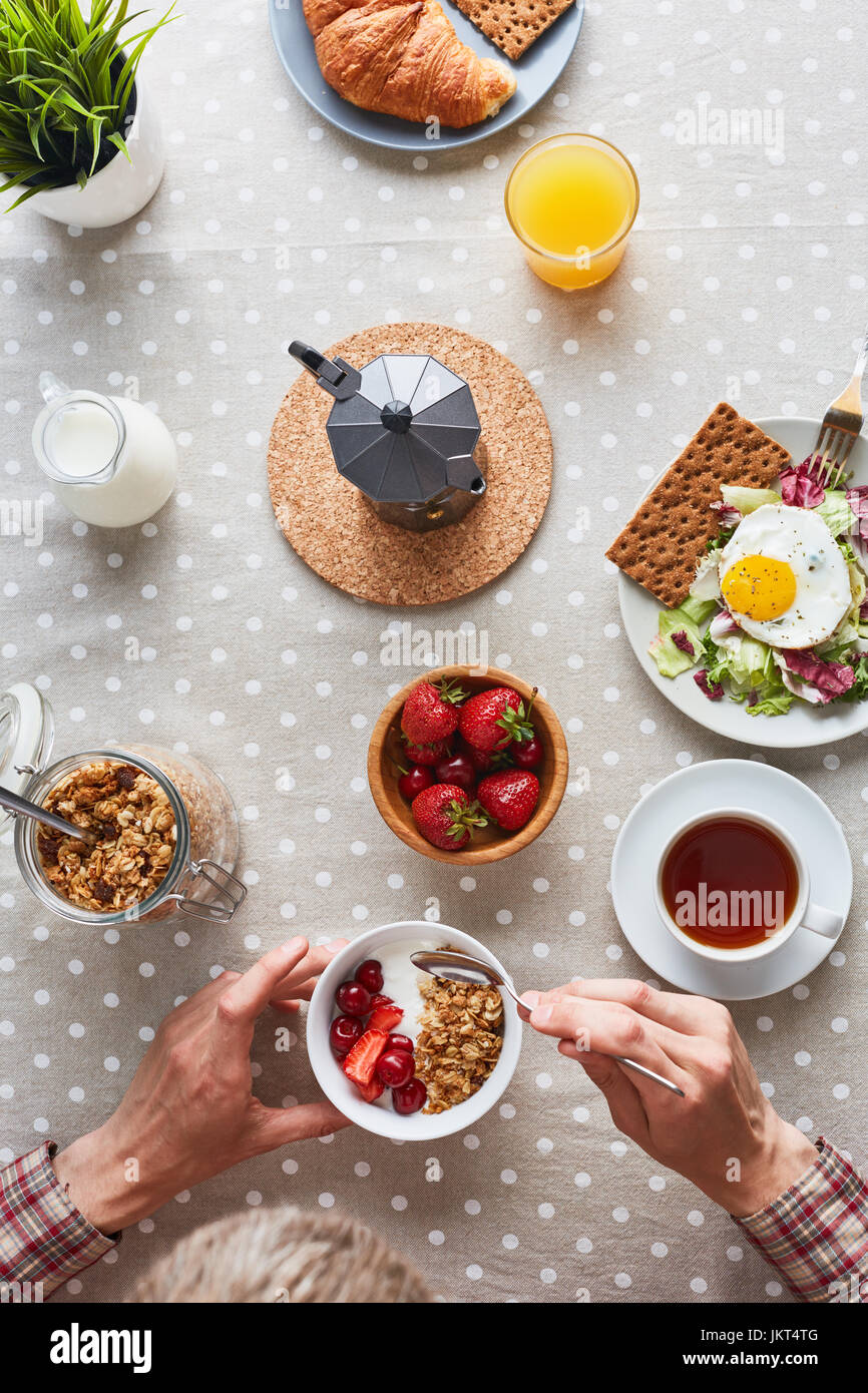 Man eating healthy breakfast by served table Stock Photo - Alamy
