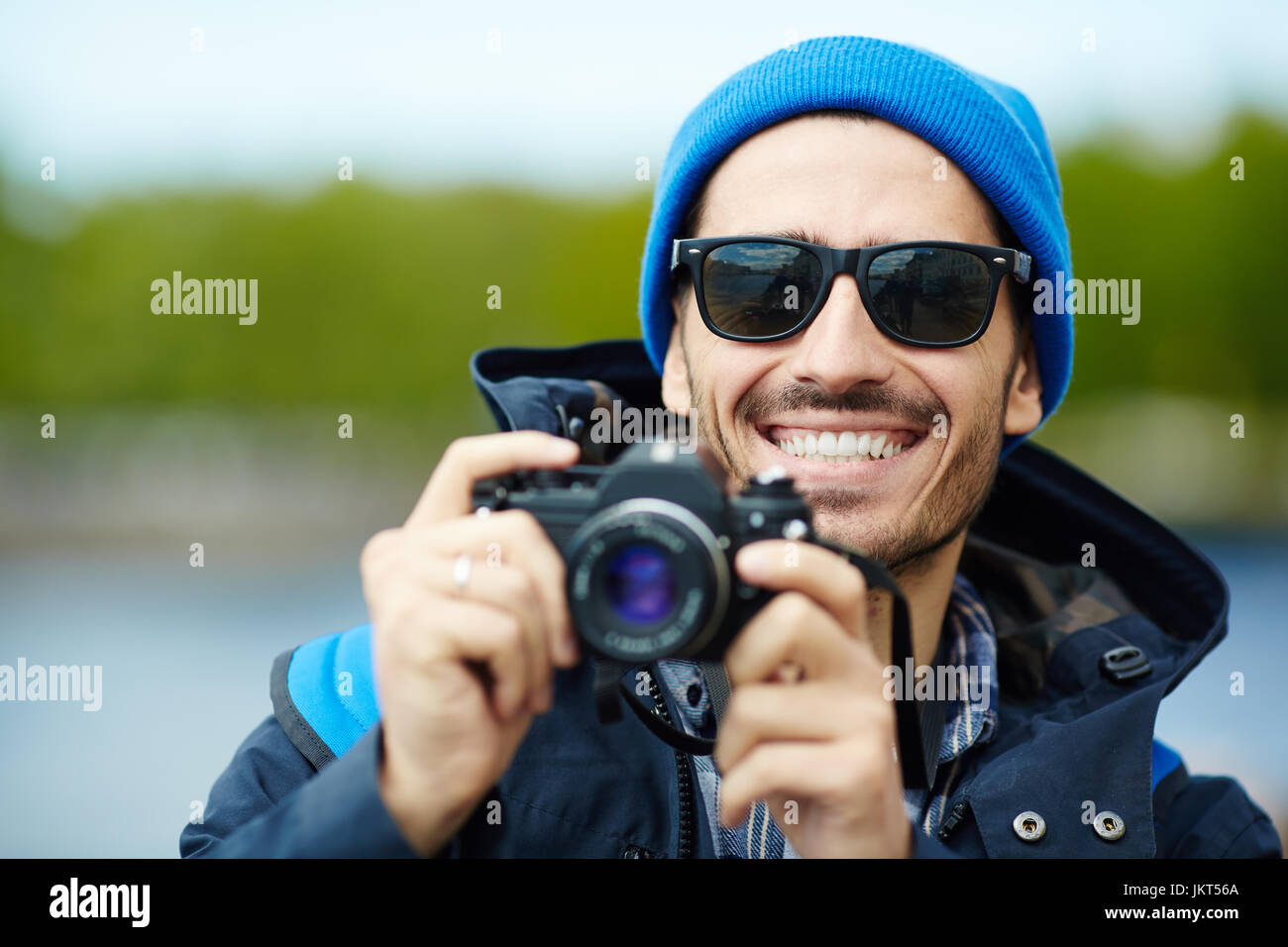Portrait of happy young man taking pictures with photo camera enjoying ...