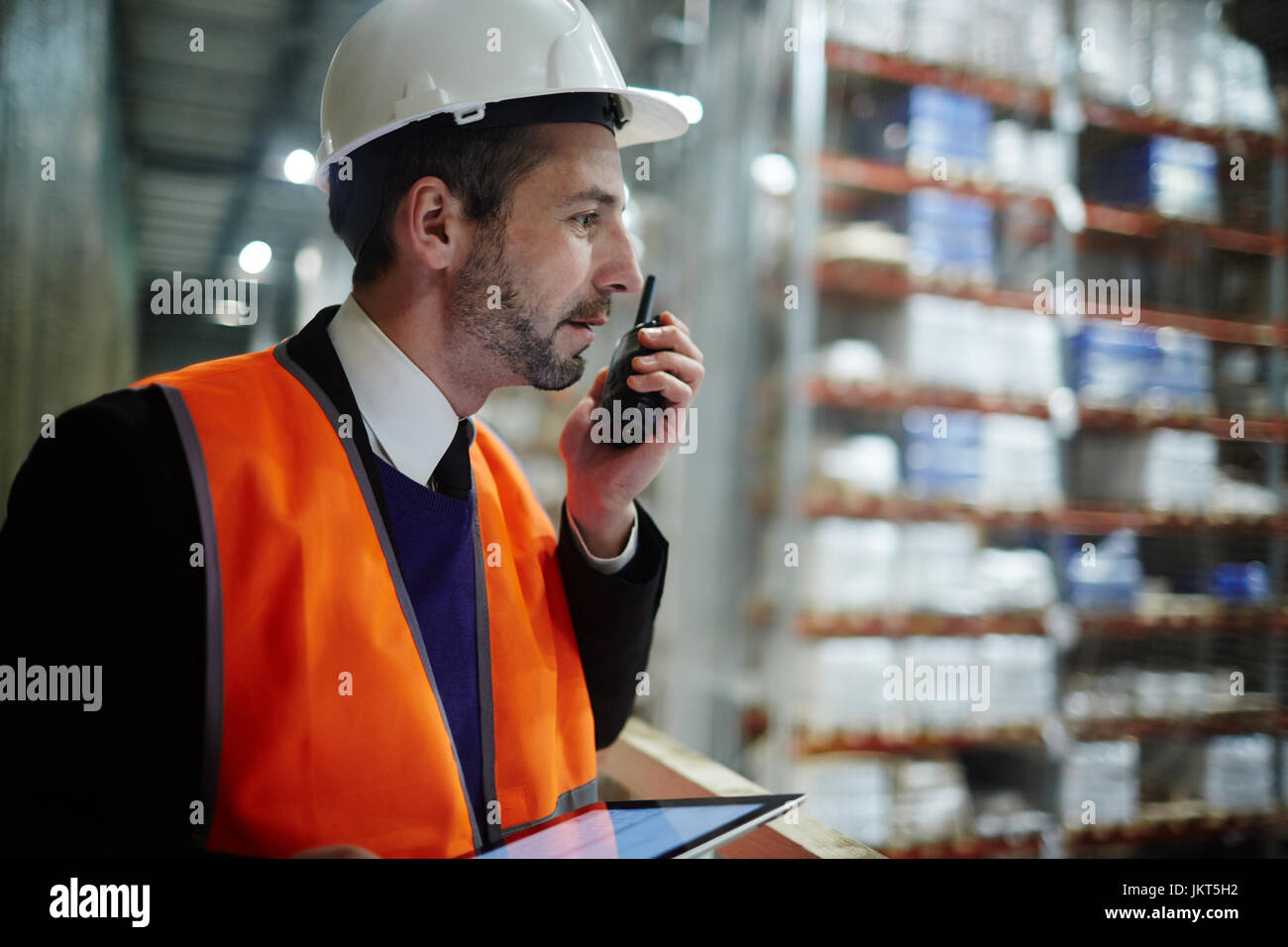 Side view portrait of warehouse supervisor speaking by walkie-talkie ...