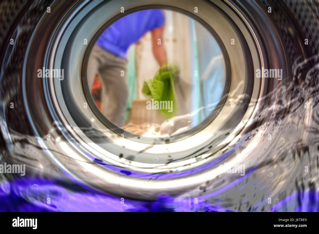 Man putting color clothes into washing machine. inside view Stock Photo ...
