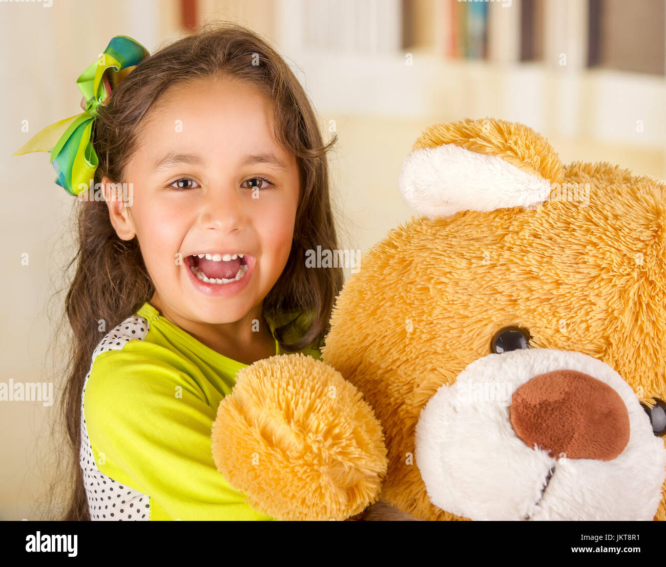A portrait of a young pretty girl smiling and hugging her teddy bear ...