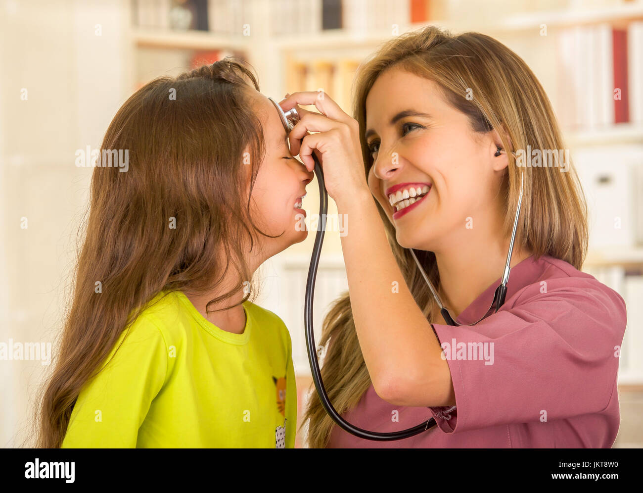 Young pretty girl smiling while a beautiful smiling doctor examining ...