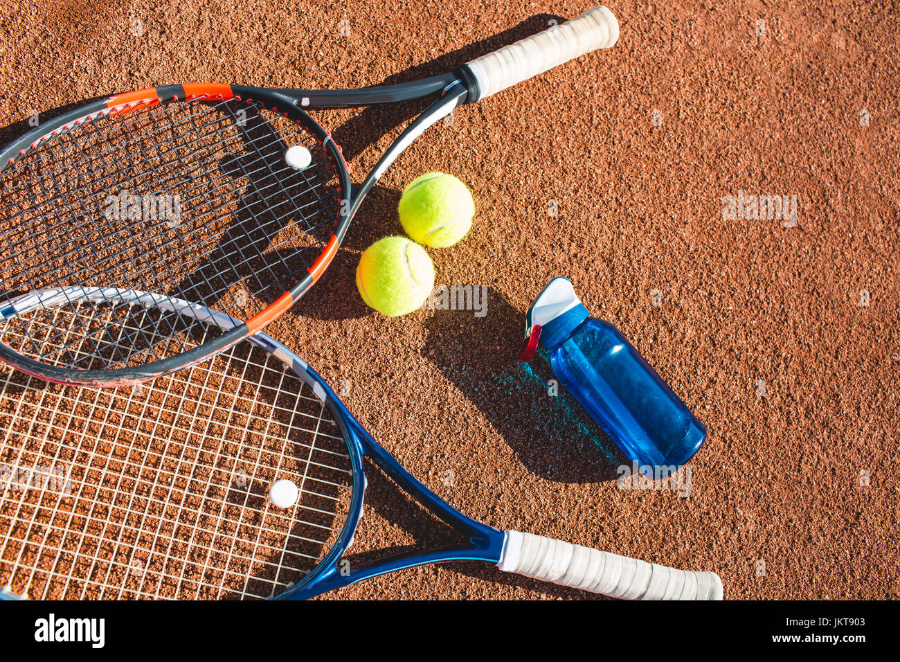 Tennis balls, rackets and bottle of water on the clay court Stock Photo ...