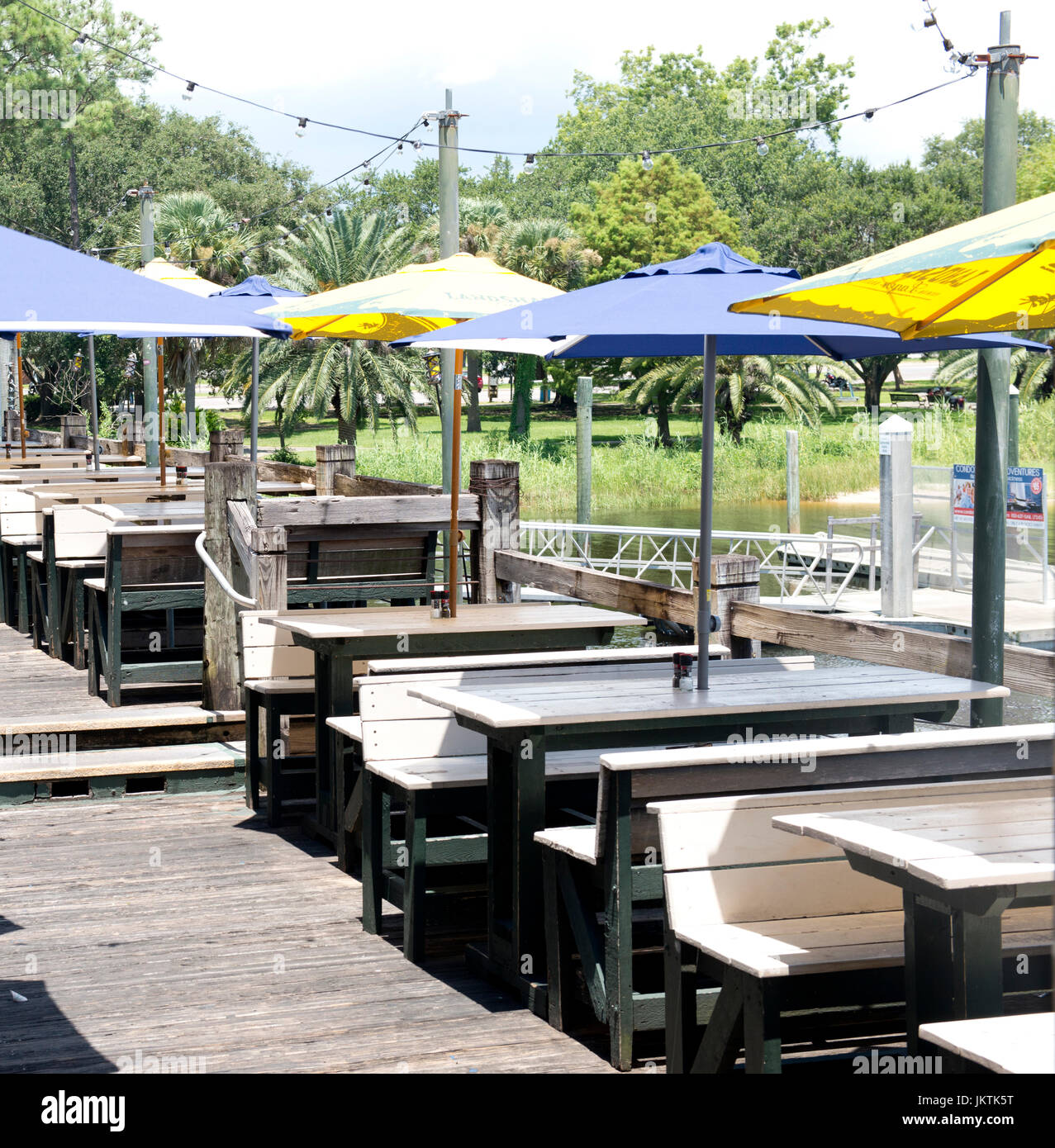 A view of an outdoor restaurant on the waterfront. There are wooden ...