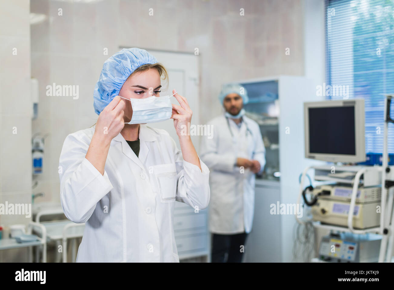 Confident Vietnamese doctor putting on medical face mask while ...