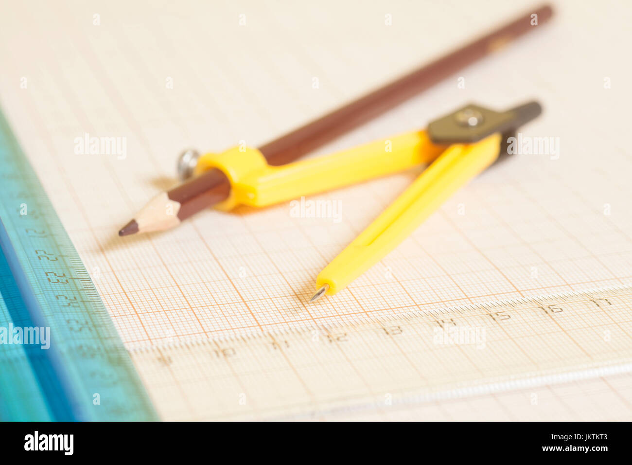 Yellow Drawing compass with pensil and rulers on graph paper ...