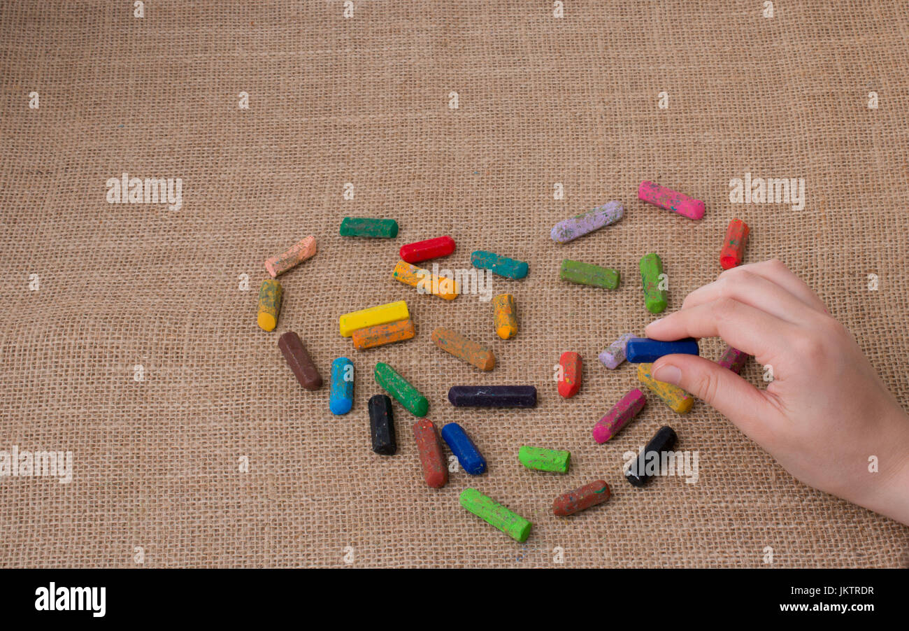 Hand holding a crayon by crayons forming a heart shape Stock Photo - Alamy